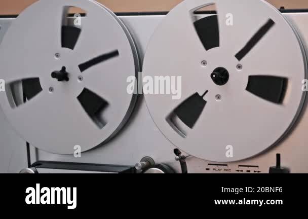 A hand reaches to press the stop button on a vintage reel-to-reel tape ...