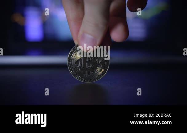 An upclose view of a hand grasping a cryptocurrency coin while ...