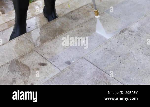 Cleaning service employee washing stone steps with pressure washer ...