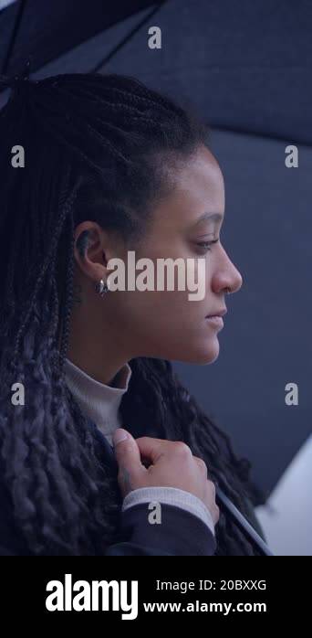 A thoughtful woman quietly sheltered by an umbrella, embodying ...