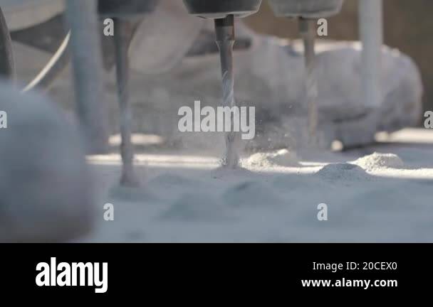 Drill bits are actively in use, generating dust clouds in a bustling ...