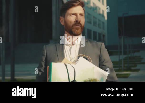 Depressed office worker man walking with box of personal stuff at ...