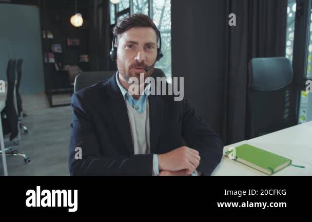 Portrait handsome man uses headphone for work speaking look at camera ...