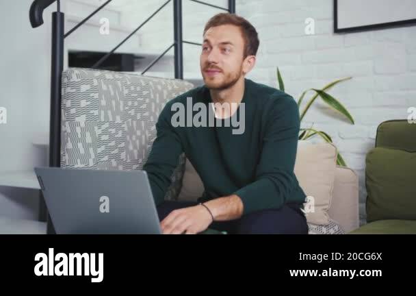 Handsome man calling woman sitting on sofa enjoying using laptop ...