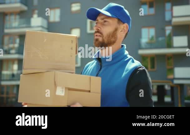 Close up tired attractive young delivery man holding cardboard box ...