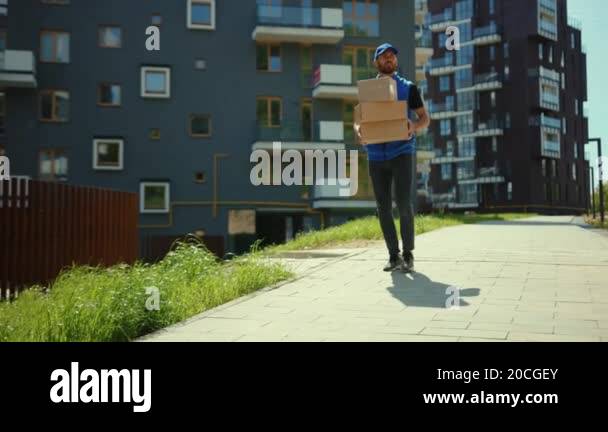 Close up attractive young delivery man holding cardboard falling boxes ...