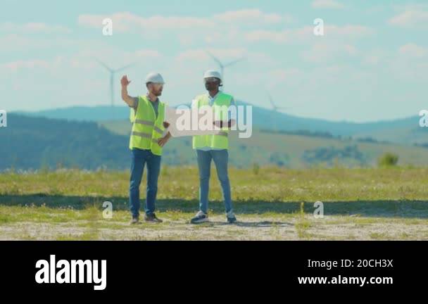 Engineers men stand with project plan near windmills in fields team ...