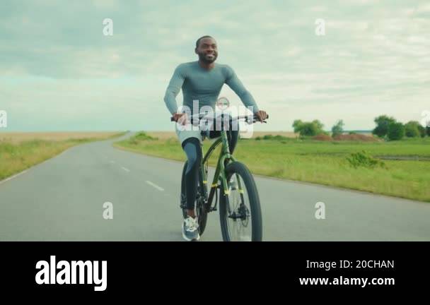 Close up smiling african american man in cycling on road in the ...