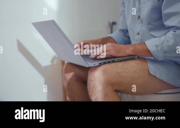 Worried businessman working on laptop wearing mask sit on the toilet at ...