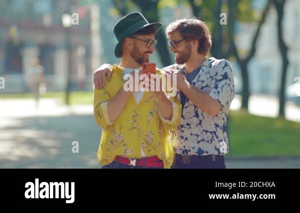 Young two gay men stand use phone at sunlight feel happy homosexual ...