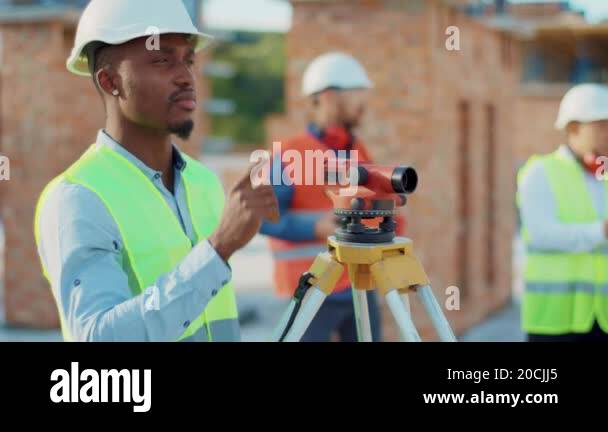 African american man engineer surveyor takes measures with theodolite ...