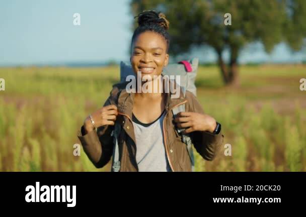 Adventurous afro-american female tourist with large backpack smiling ...