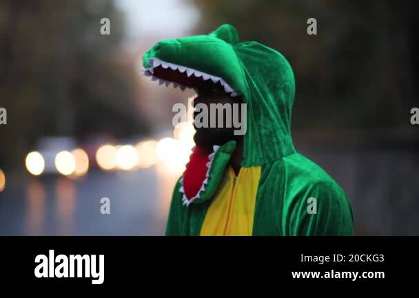 Funny afro-american guy in colorful dino costume standing on busy ...
