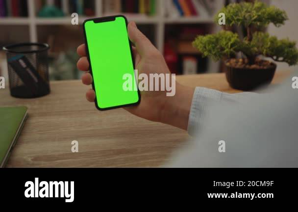 NEW YORK - May 19, 2019: Hand man uses holding mobile phone with vertical green screen table ...
