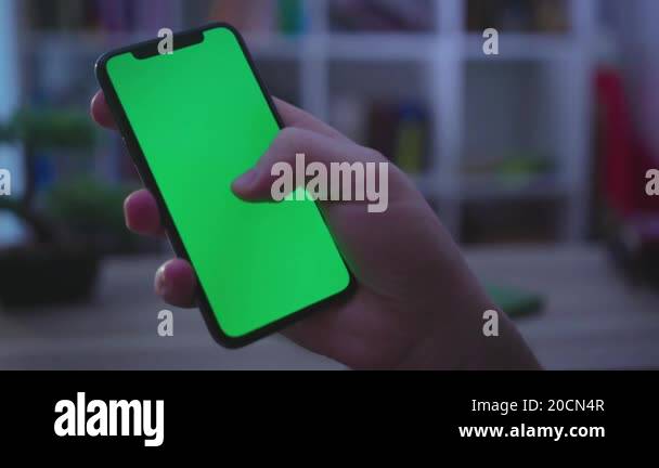 NEW YORK - May 19, 2019: Young hands man hold phone with vertical green screen use touch digital ...