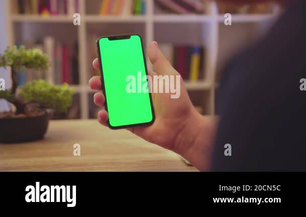 NEW YORK - May 19, 2019: Close up hands man hold phone with vertical green screen use touch ...