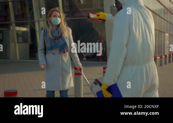 Medical worker in a protective suit try screening passenger to check ...