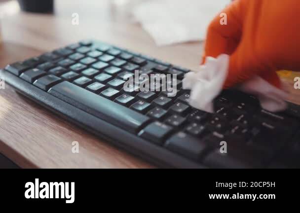 In gloves hands disinfecting laptop keyboard with antiseptic spray and ...