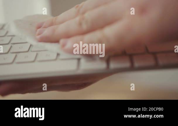 Close-up of male hands disinfecting white computer keyboard with ...