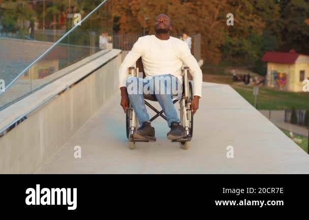Happy handsome disabled man rides in wheelchair at sunlight smiling ...