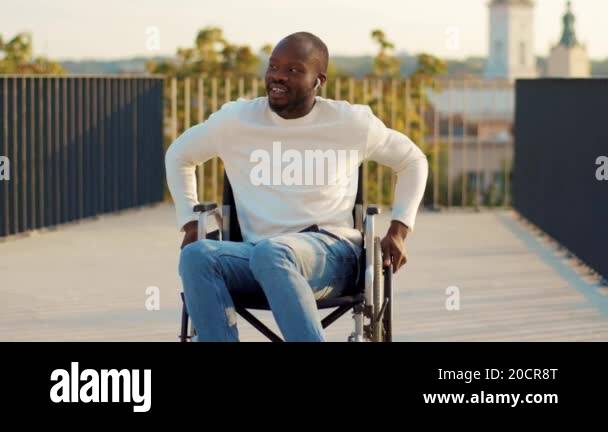 Close up young man use headphones speaking phone on a wheelchair in a ...