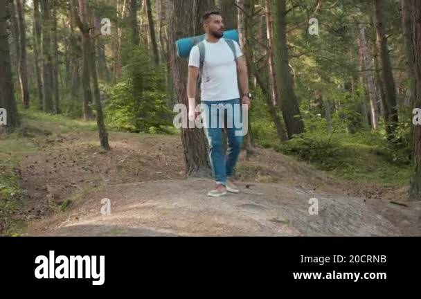 Tired handsome young man hiker standing in the forest look around at ...