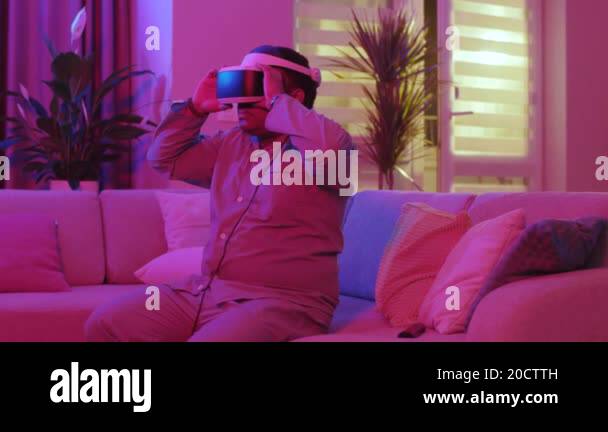 Smiling mixed race young man removes virtual reality headset sitting on ...