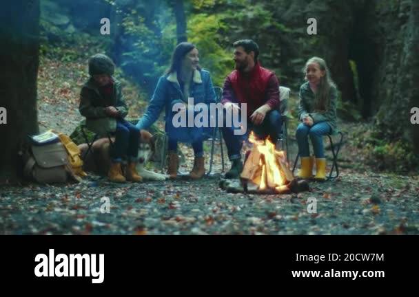 Smiling family sits near campfire on autumn evening. Children with ...