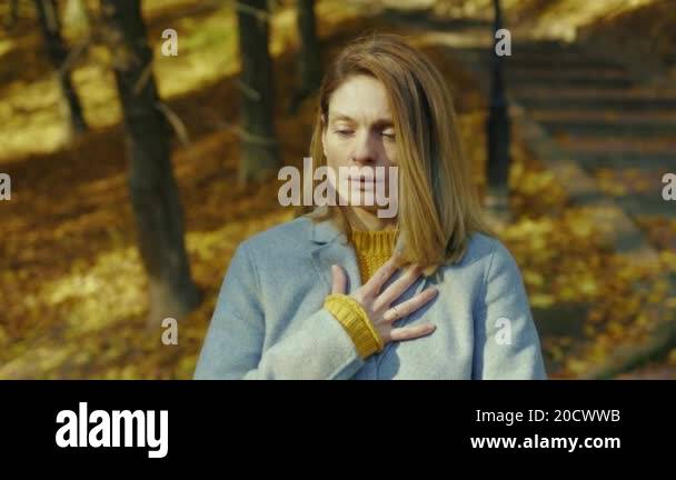 Tired sick young woman look at camera feel cold in autumn park at ...