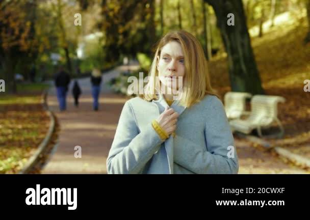 Woman face sick feel cold sneezes coughs walking look around in autumn ...