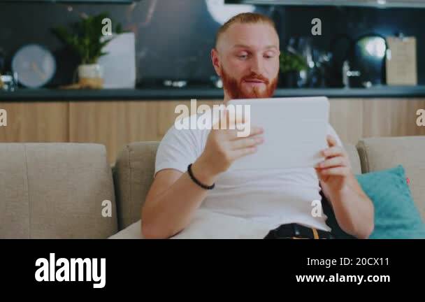 Handsome man using tablet computer. Speaking on video call. Sitting on ...