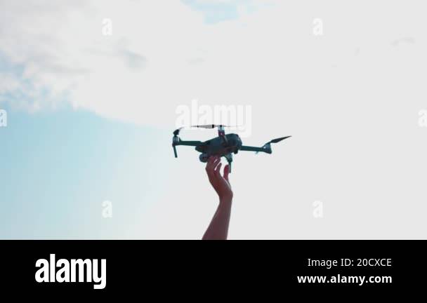 Mans hand catching flying drone in air on background of sky. Sunny ...