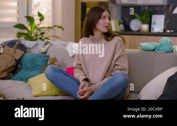 Unhappy woman look at camera shrugs shoulders sitting on sofa on background father and daughter ...