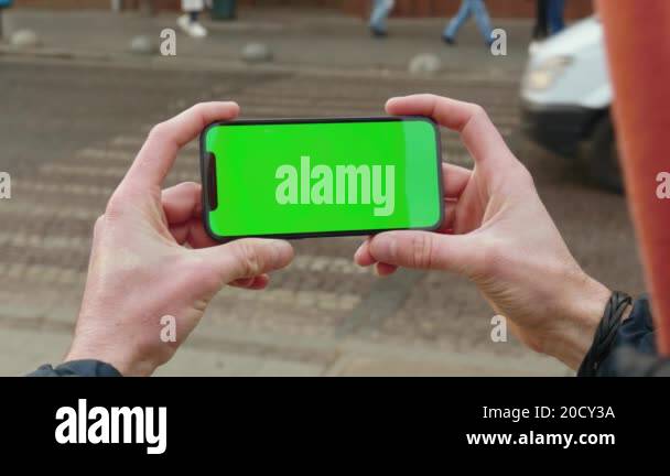 Close up man hand using and tapping phone with horizontal green screen ...