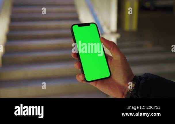 Shot of hands man holding and touching the phone with vertical green ...