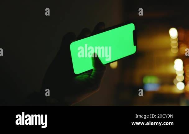 Close up hands man use phone with vertical green screen stand at night ...