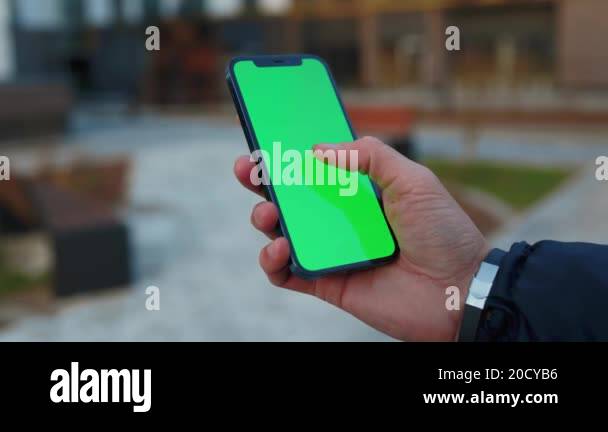 NEW YORK - December, 19 2020: Hands man use phone with vertical green screen stand on street ...