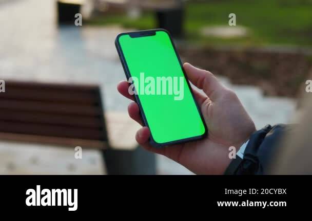 NEW YORK - December, 19 2020: At sunlight young hands man holding use phone with vertical green ...