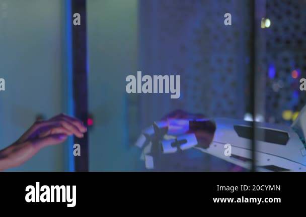 Man hand touch finger with a cybernetic robot through the window glass ...