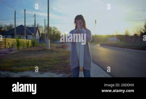 Woman outdoors with arms raised to the sky, looking up with hope and ...