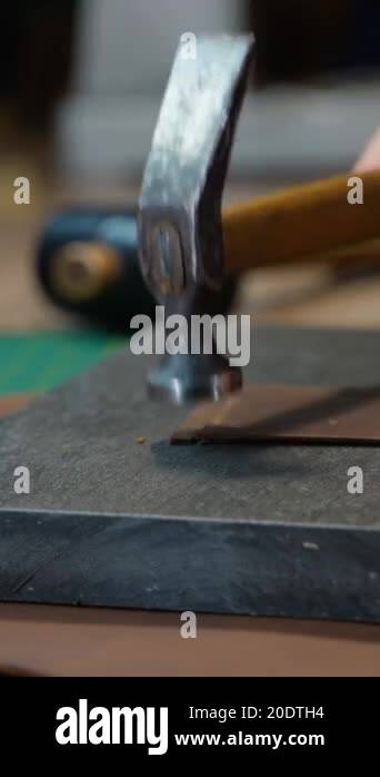 Close-up of a craftsman using a hammer to work on leather ...