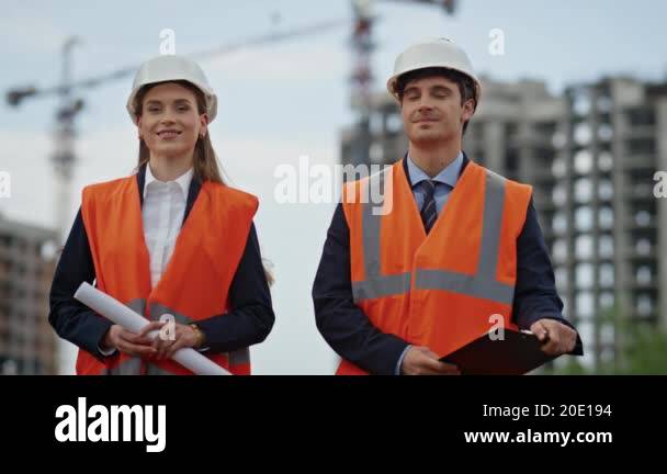 Happy engineers posing at construction site holding blueprints closeup ...