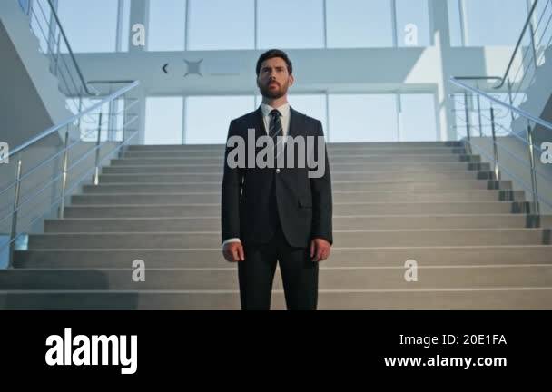 Serious executive standing confidently in light office interior closeup ...