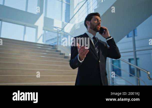Rich man talking cellphone in modern office building. Confident executive manager in suit ...