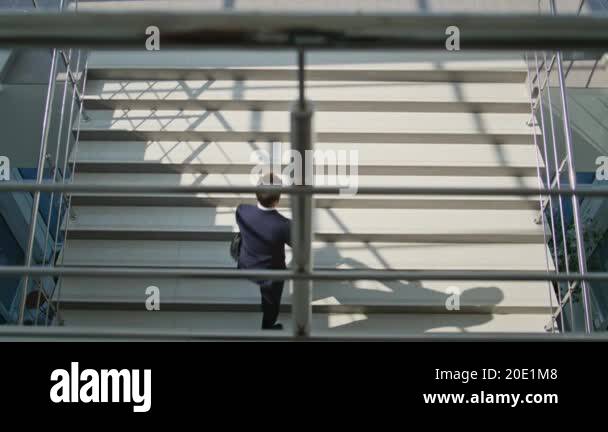 Confident professional ascending stairs in modern office building ...