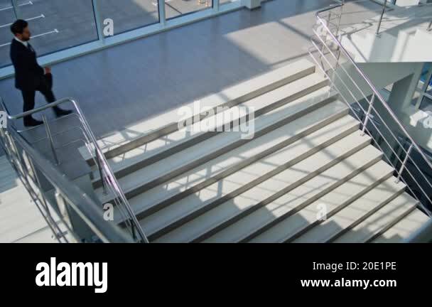 Confident businessman walking down staircase modern office interior ...