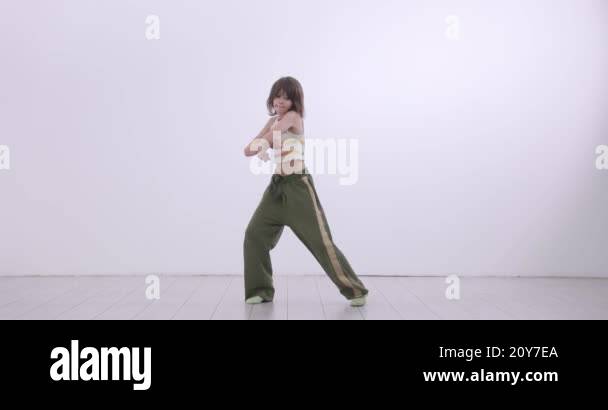 Girl performed fiery dance in a white studio. Teenager with rhythmic movements and facial ...