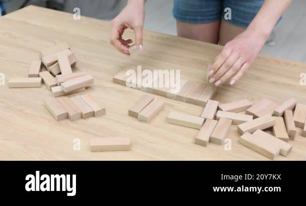 Woman stacks wooden play blocks in row. Creating a wooden block ...