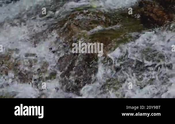 Closeup rapid fresh water flowing from cascade range through the rocks ...