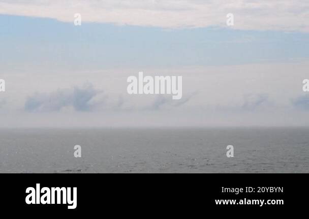 Fast moving of clouds on sky and fog over the water surface of the sea ...
